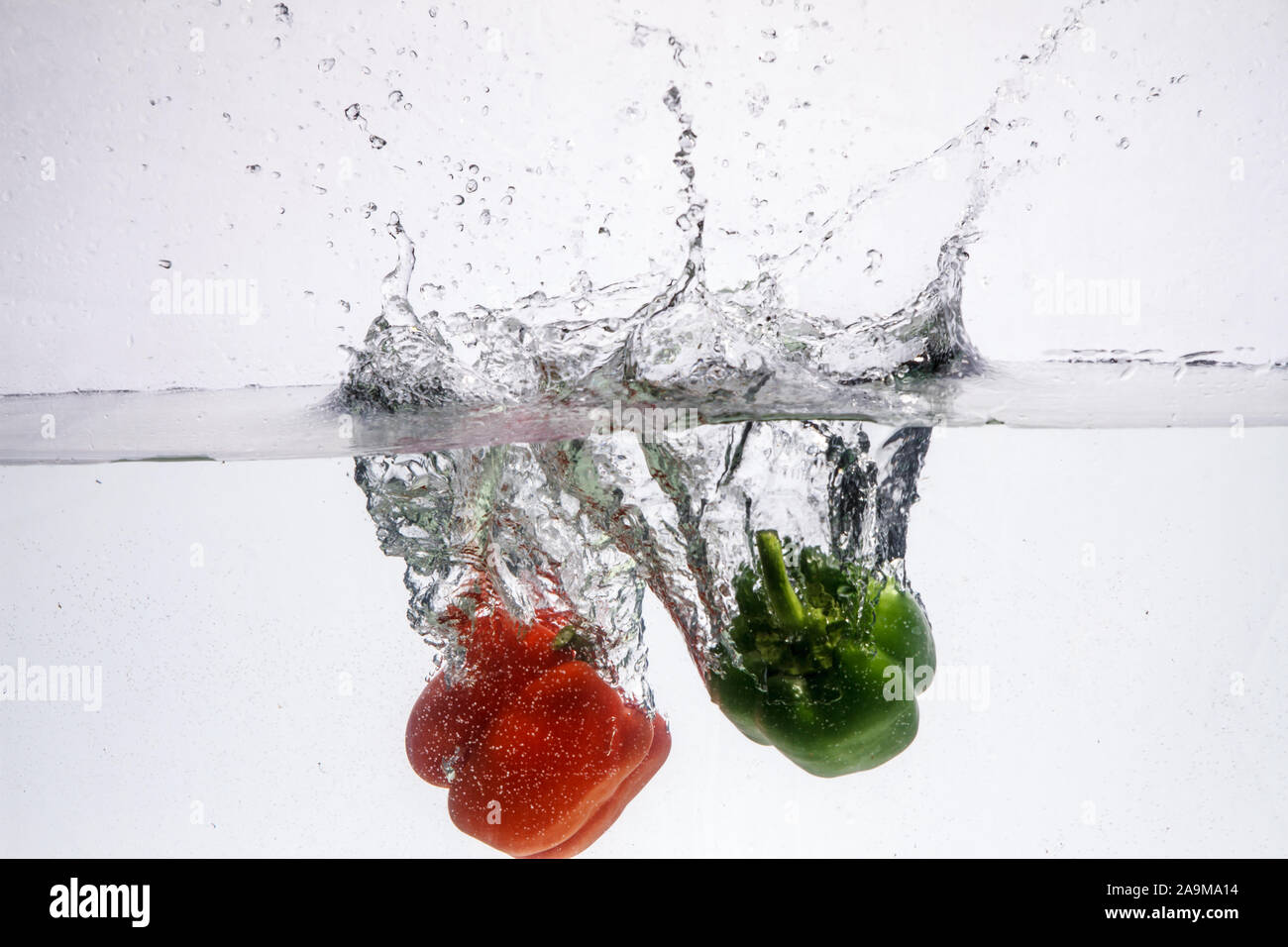 three peppers falling in water. splash of water and fruit floating in ...