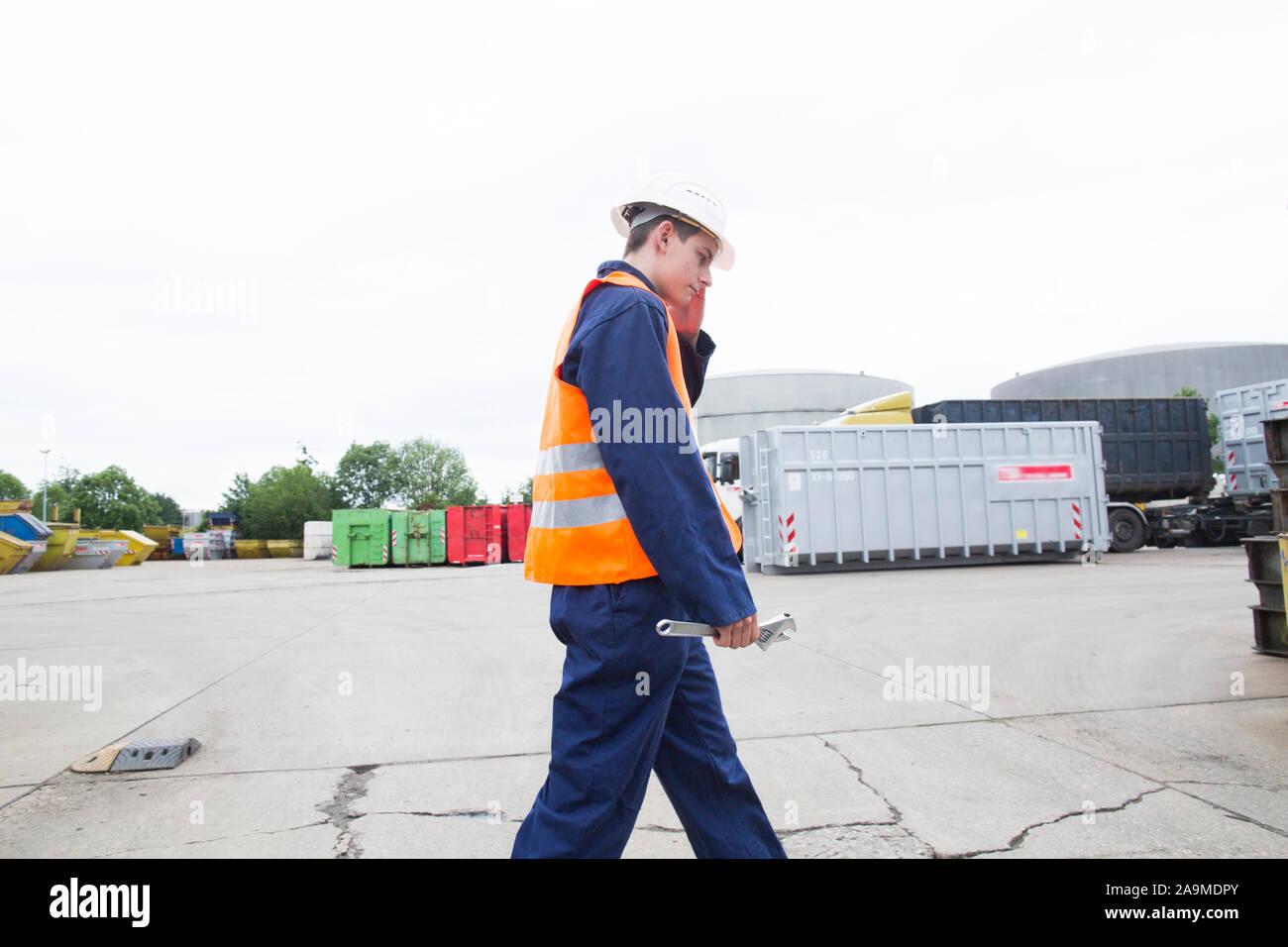worker young male with helmet outside walking Stock Photo - Alamy