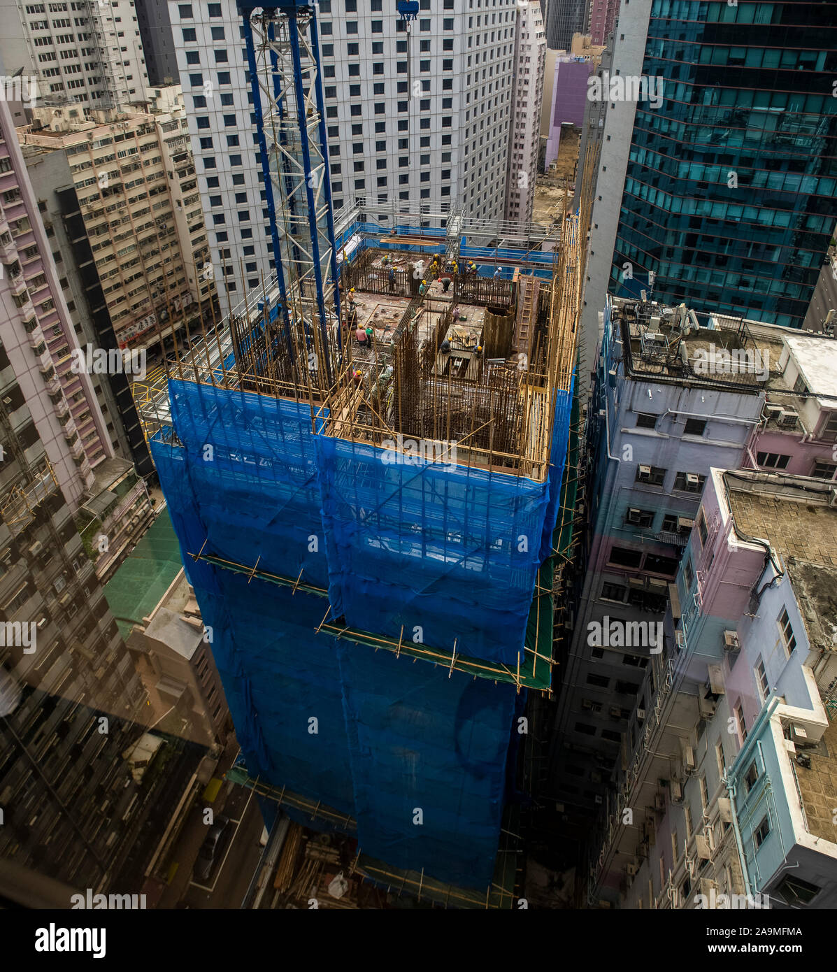 Bamboo scaffolding in Hong Kong at the top of a skyscraper under development with workers who ...
