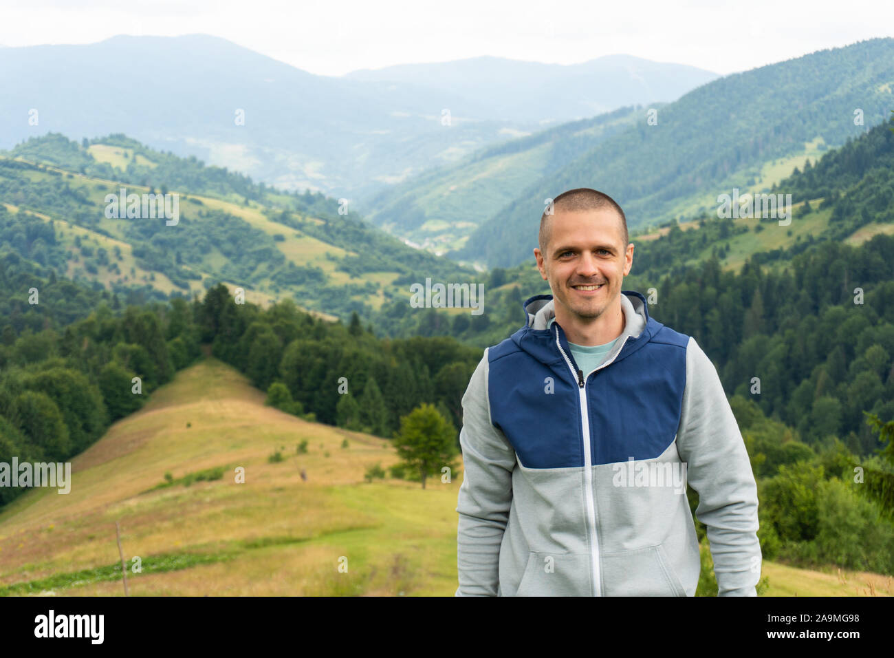 Smiling man looking in camera with mountain view behind Stock Photo - Alamy