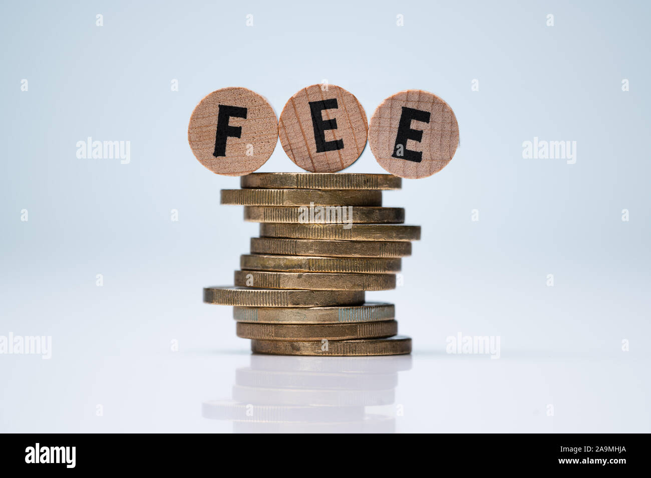 Wooden Blocks With Fee Text Above Stack Of Coins On Reflective Desk ...