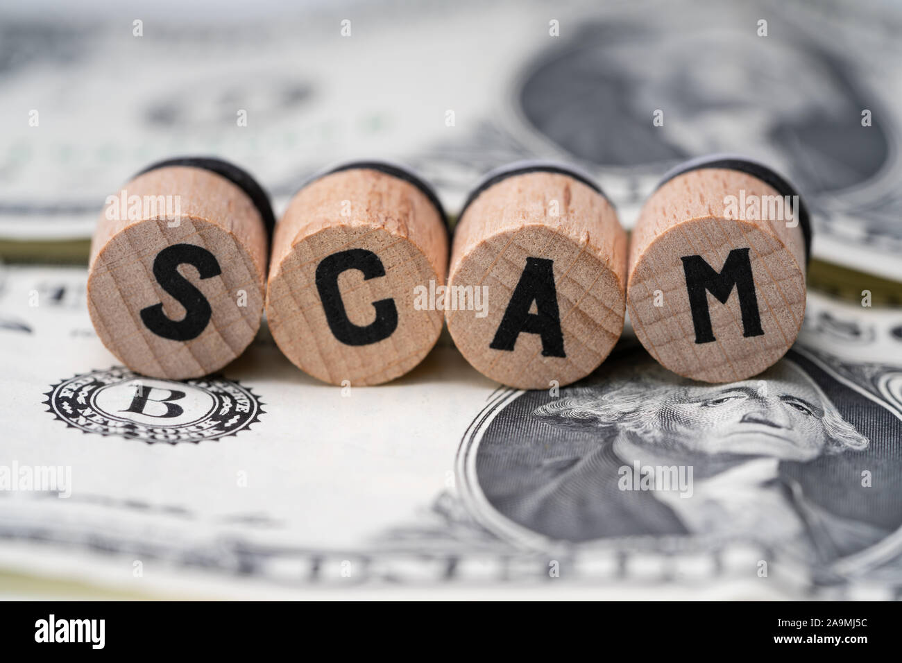 Close-up Of A Scam Word On Round Wooden Blocks Over Dollar Bill Stock ...