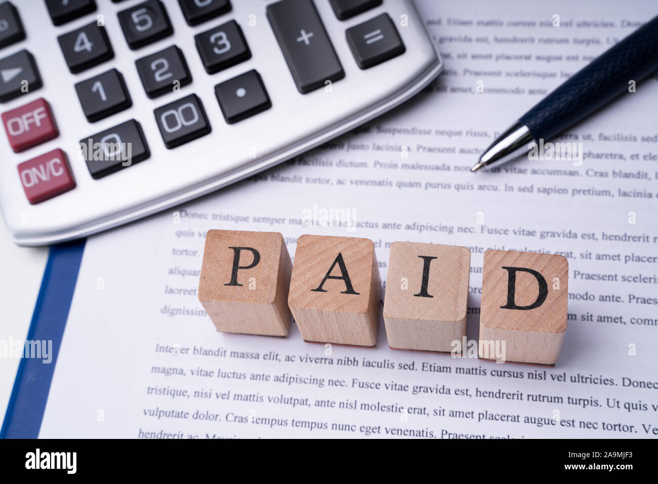 Overhead View Of Paid Text On Wooden Blocks Over Office Documents With ...