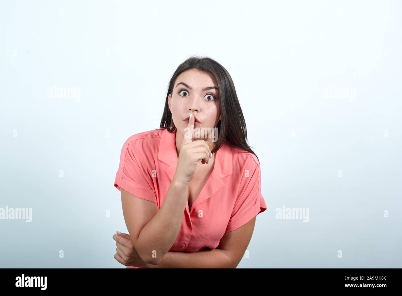 woman showing a sign of silence gesture putting finger in mouth on ...