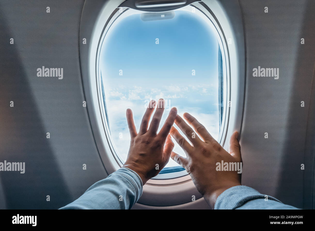 Man's and woman's hands inside touching window of airplane with clouds ...