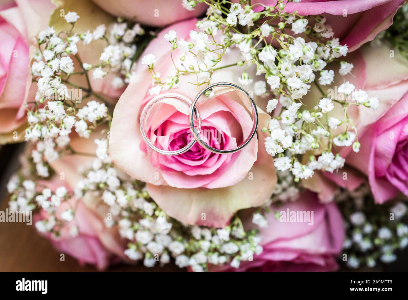 Wedding bouquet with pink roses on wooden table with rings. Wedding ...