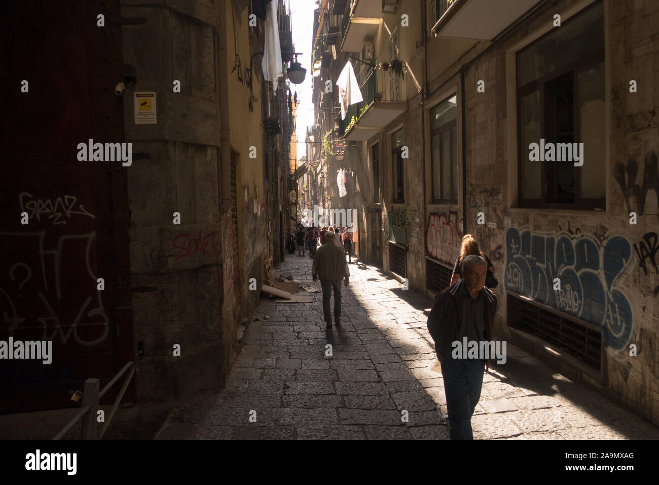 Sun coming through the buildings in a narrow alleyway in Naples city ...