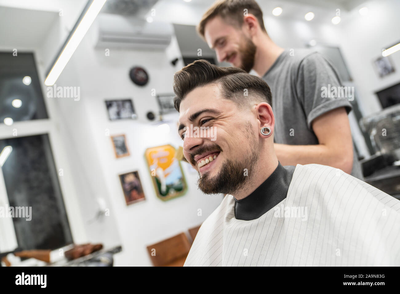 Customer smiling in barber shop with barber. Fun barber Stock Photo - Alamy