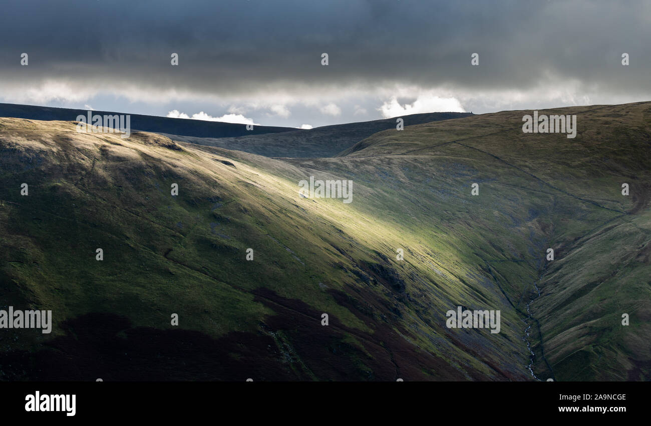 Patchy sunlight falling onto mountain ridge in Lake District National ...
