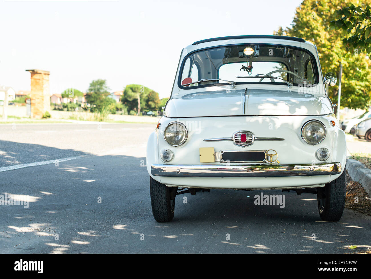 White small vintage car on the street. No people. Asphalt village road ...