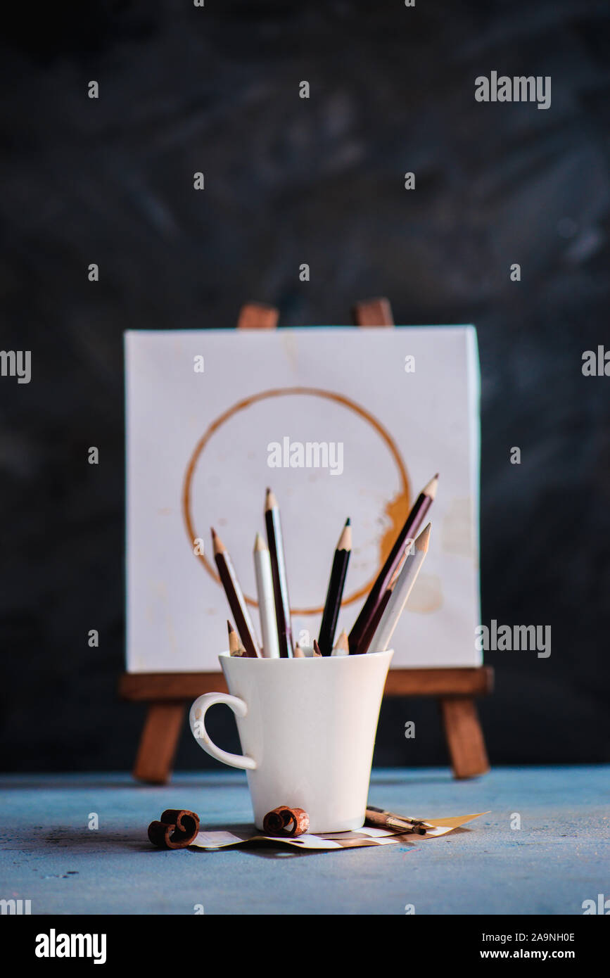 Coffee cup with pencils in front and of coffee stain painting on an ...