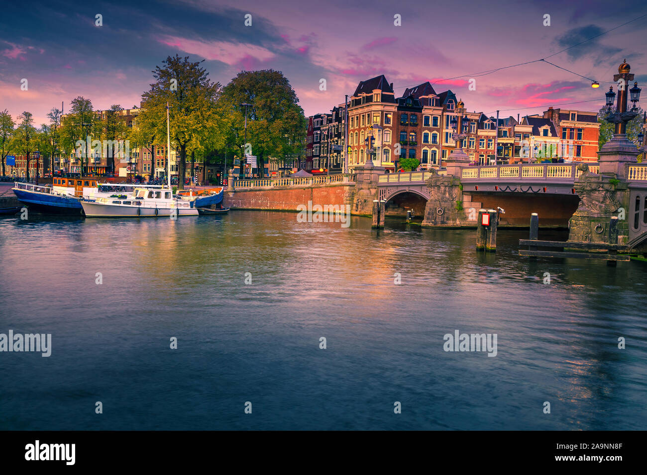 Stunning dutch cityscape with anchored boats in water canal at sunset ...