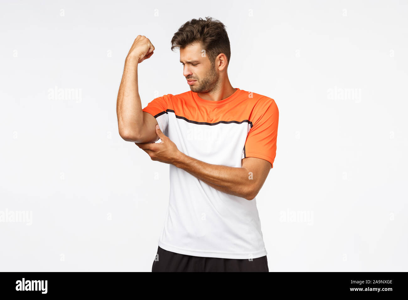 Upset gloomy handsome young man feeling weak as raising arm, touching ...