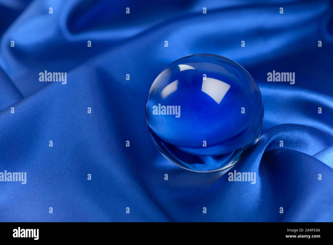Glass ball on blue silk cloth background Stock Photo - Alamy
