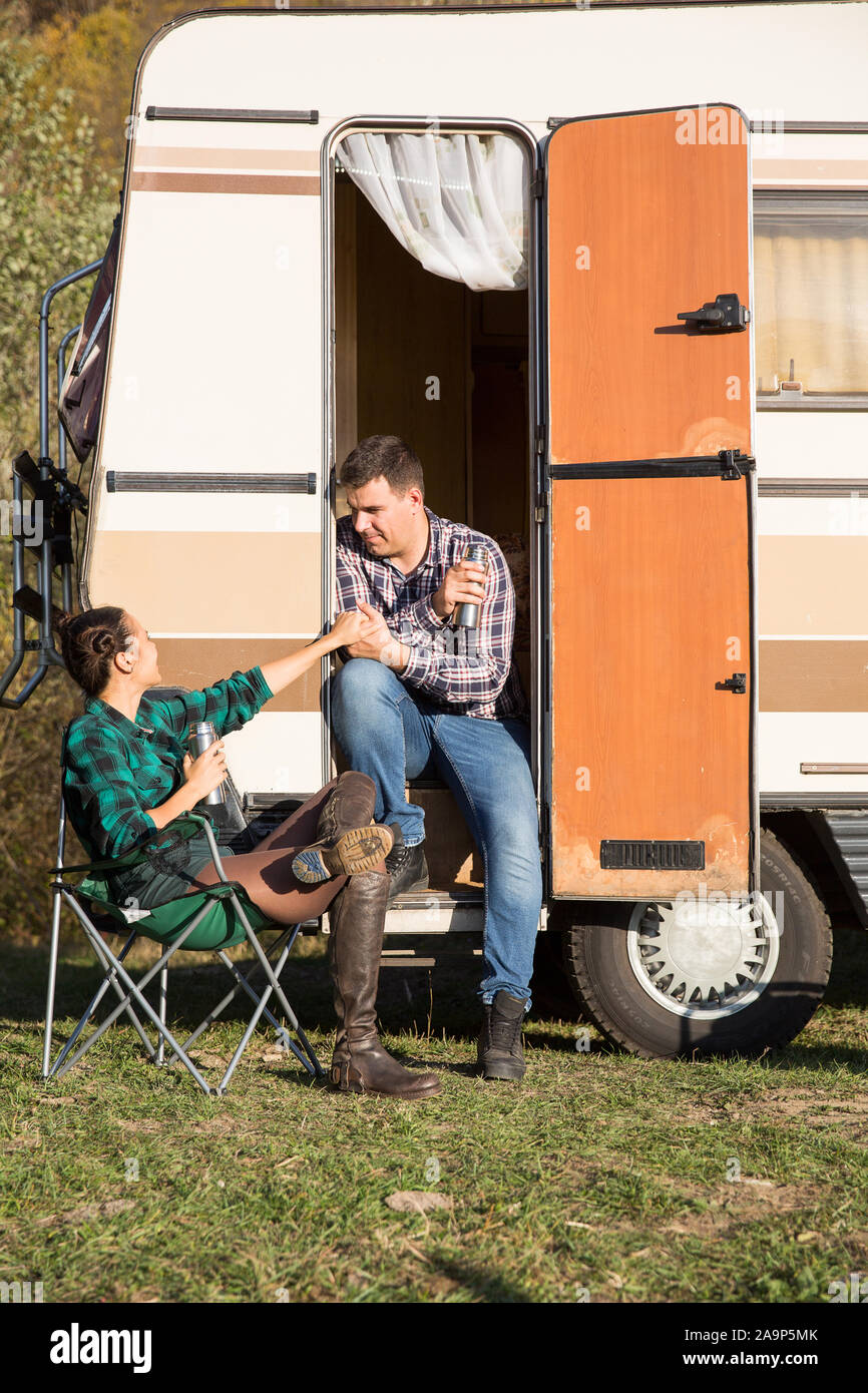 Woman sitting on camping chair and looking at her boyfriend sitting on ...