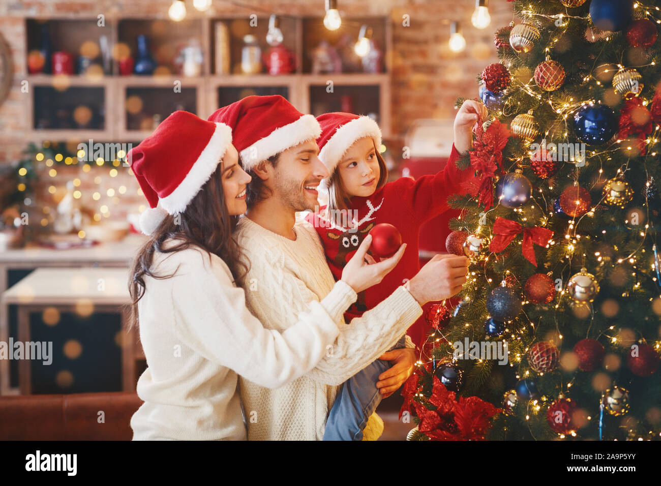 Excited young family making Christmas tree together Stock Photo - Alamy