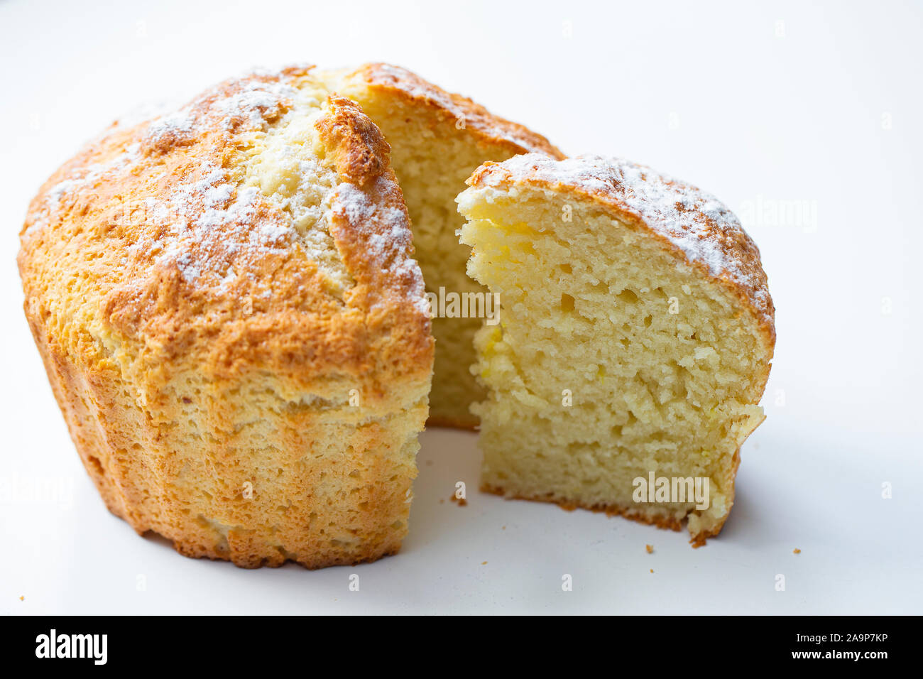 Side view of a freshly baked cupcake with a cut piece on a white ...