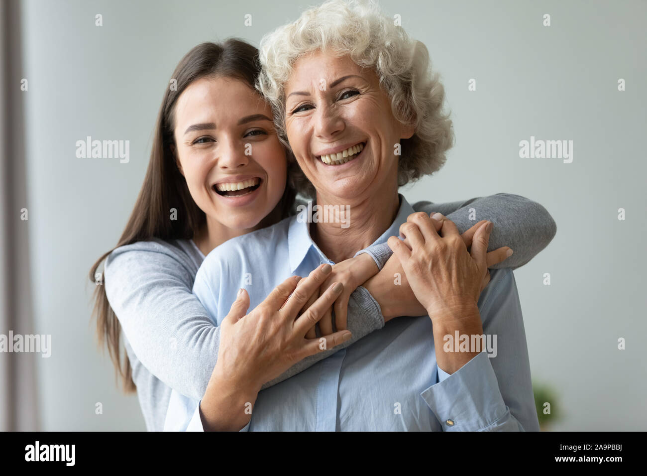 Cheerful affectionate two age generation women embracing indoors ...