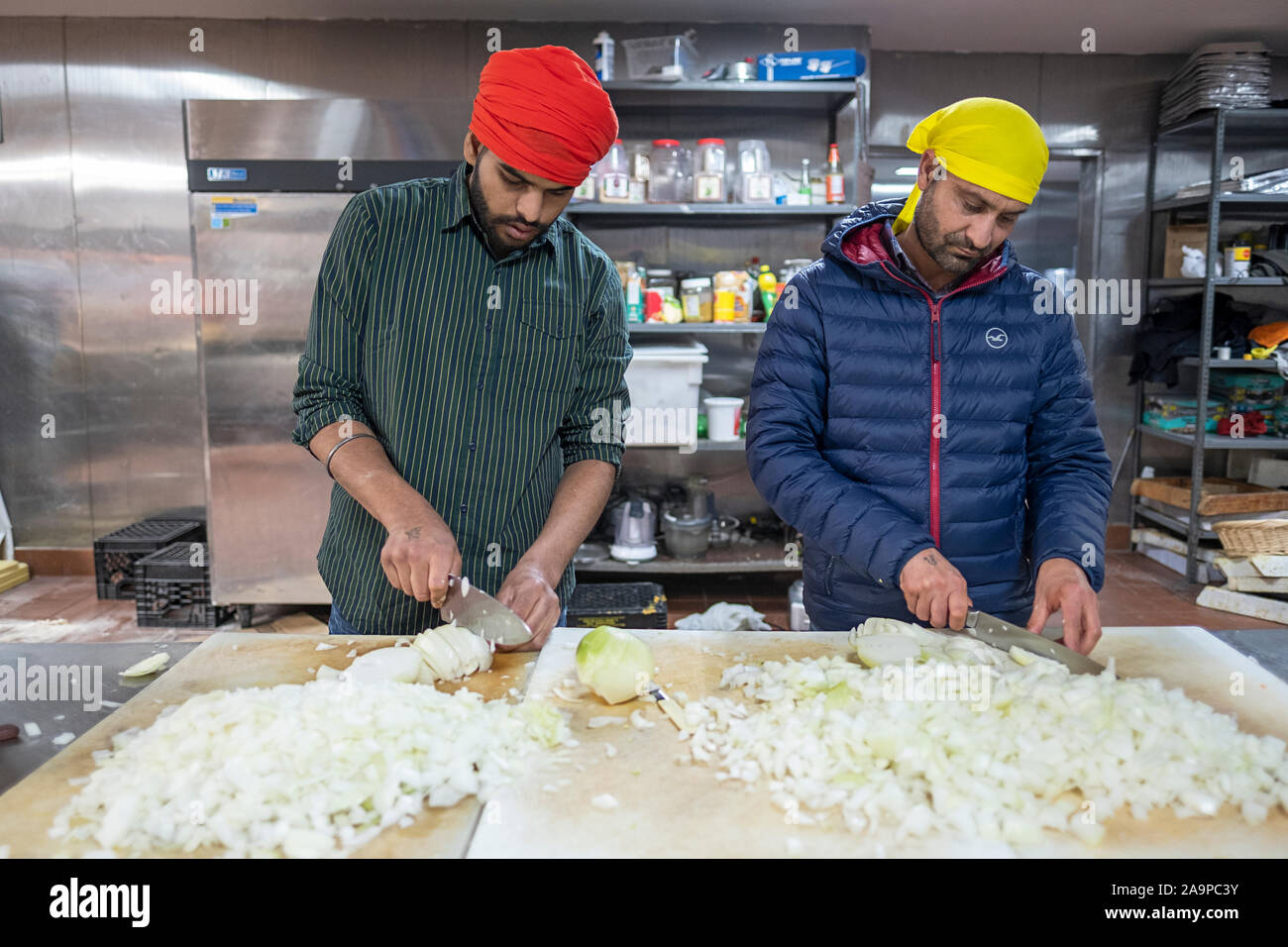 2 Sikh male volunteers cutting onions in a Langar, a free communal ...
