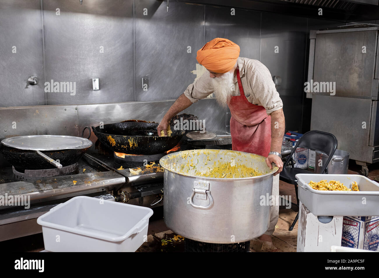 A volunteer in a langar, A Sikh temple kitchen, prepares pakora, a deep ...