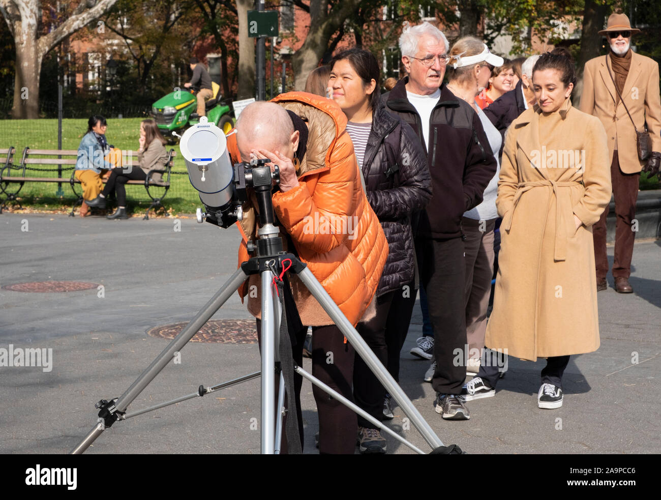Curious people of all ages line up to look though a telescope & see the ...