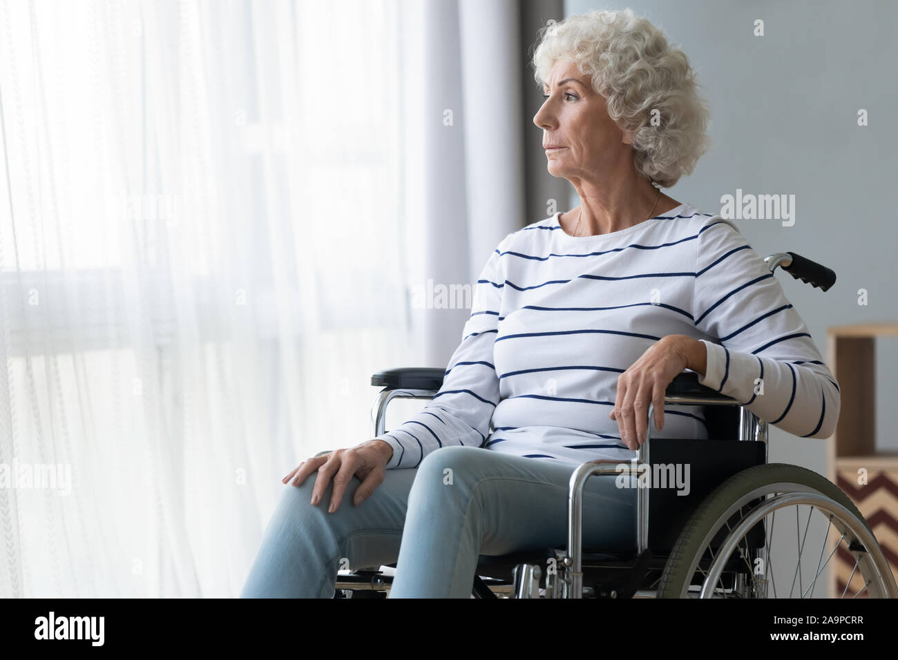 Sad paraplegic old woman sit on wheelchair look through window Stock ...