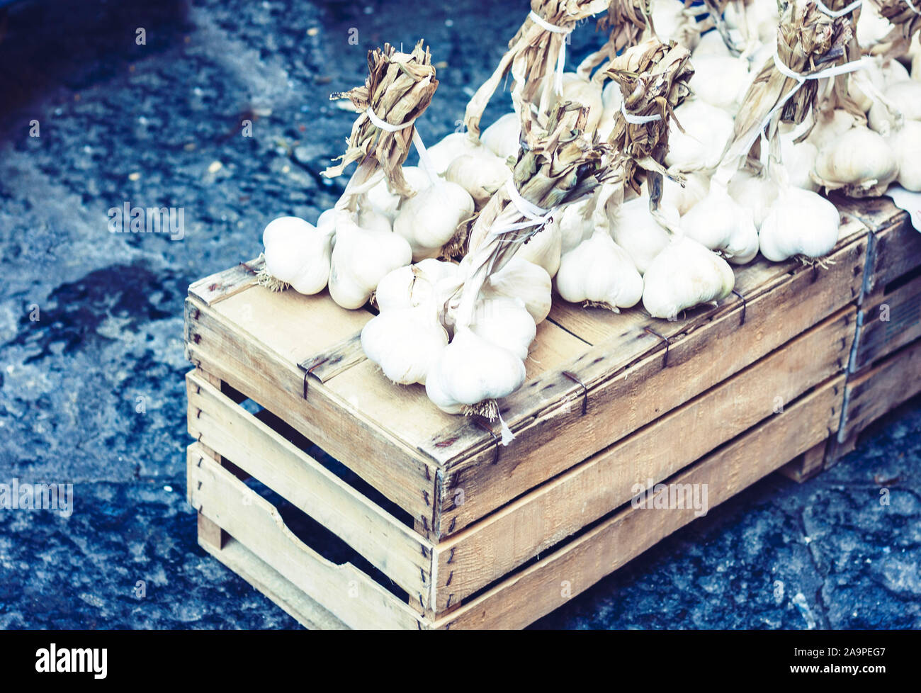 bundles of unpeeled garlic on wooden crates in the fruit market ...