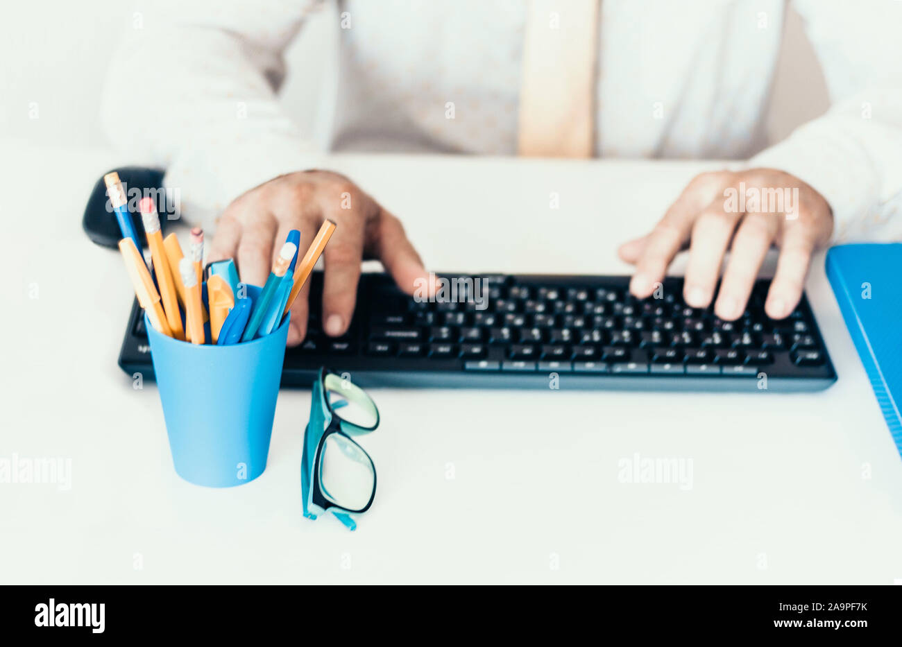 Close-up of hands middle-aged man in white shirt typing on keyboard ...