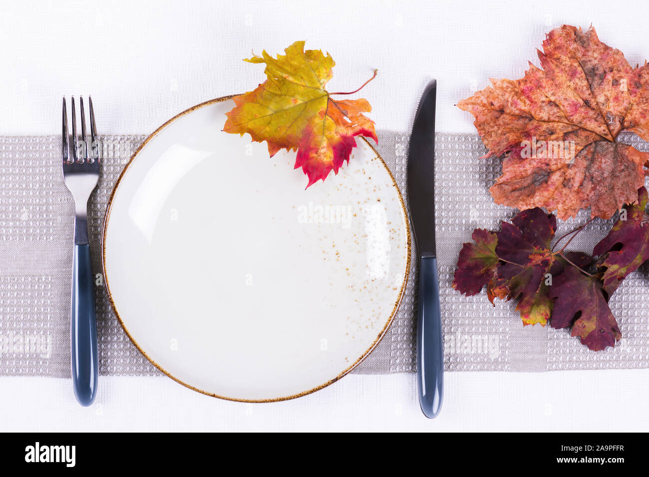 Cozy festive fall table setting with colorful autumn leaves. Minimal ...