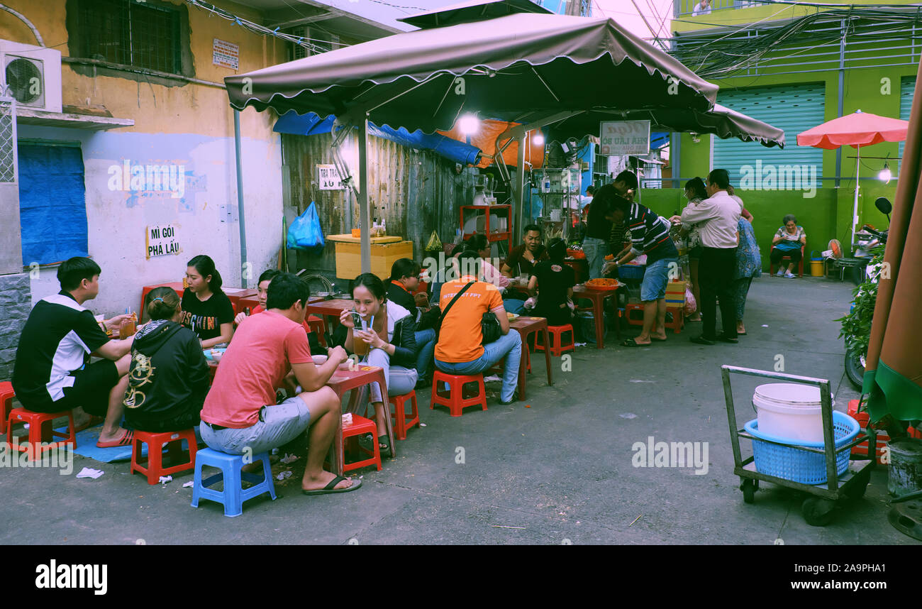 people or diners sit on plastic tables and chair outside pork offal ...
