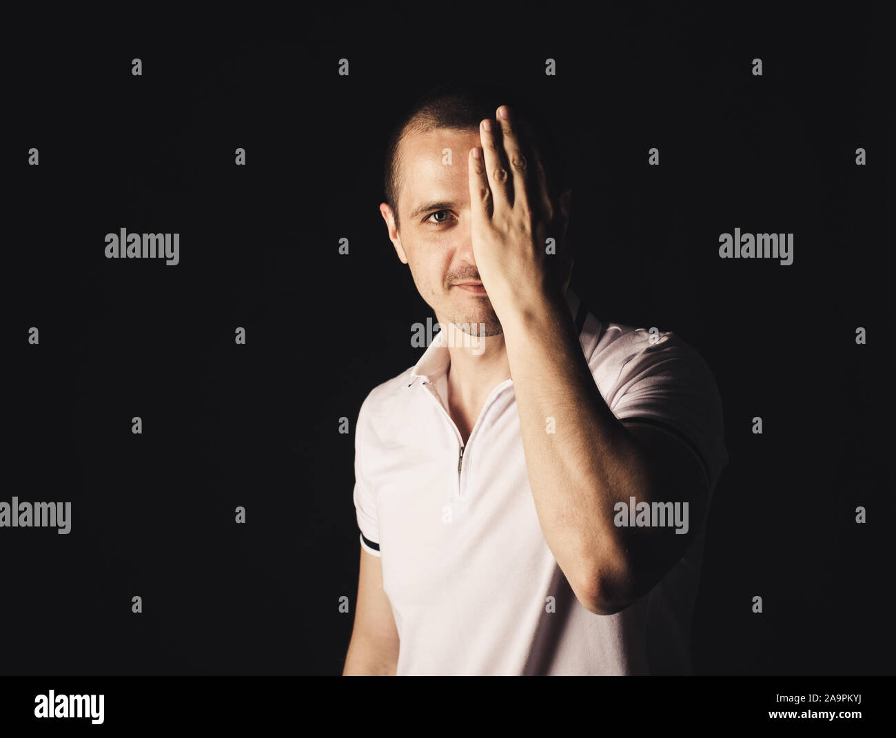 Man with half closed face by hand looking in camera Stock Photo - Alamy