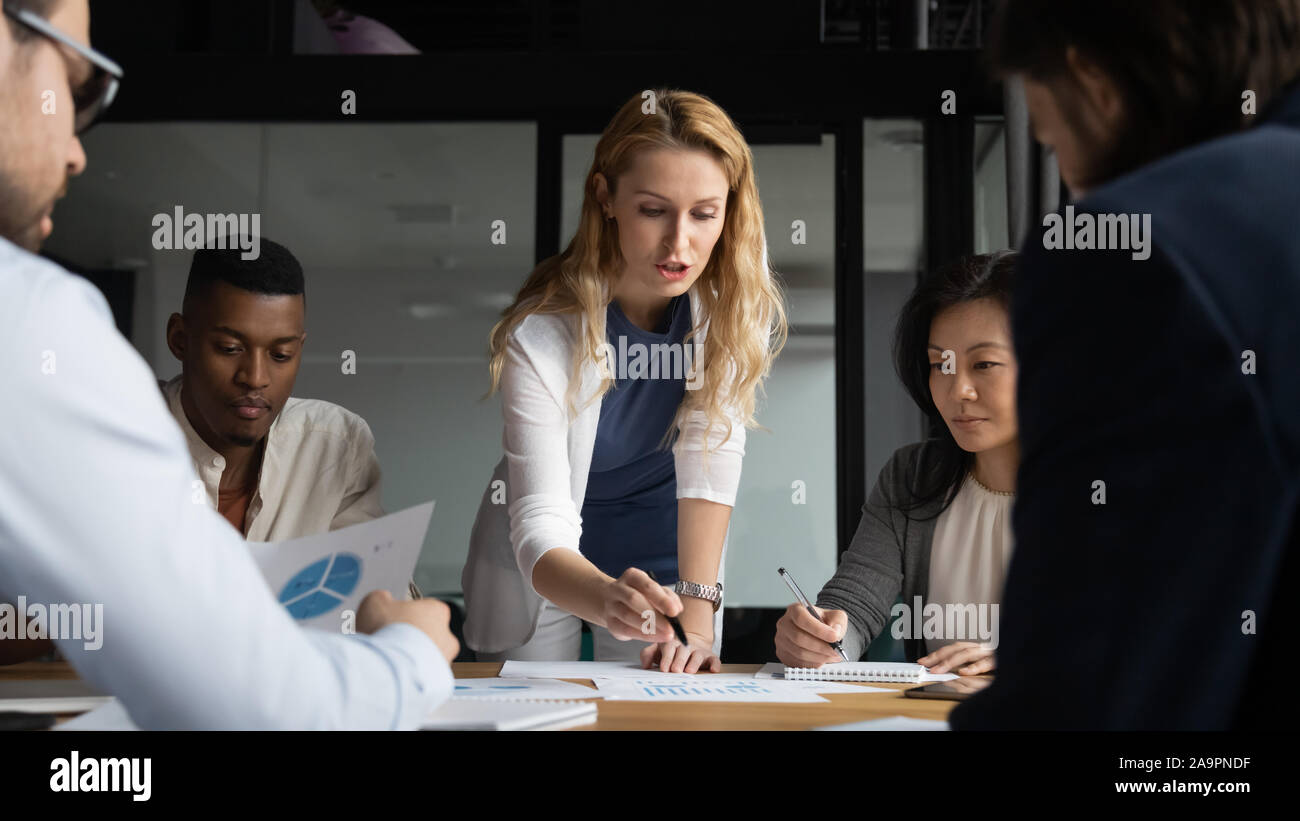 Young businesswoman explaining research results in graphs to colleagues ...