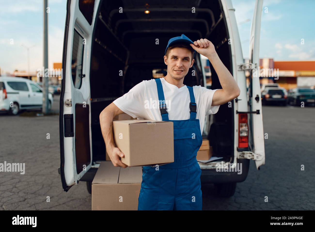 Loader in uniform holding box, delivery service Stock Photo - Alamy