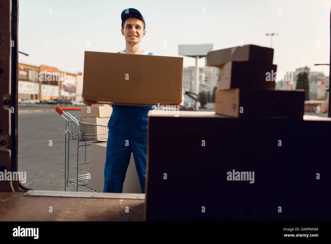 Loader in uniform holding box, delivery service Stock Photo - Alamy