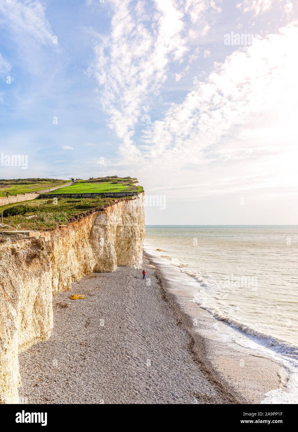 The famous chalk cliffs at Beachy Head. Waves lap onto the beach below ...