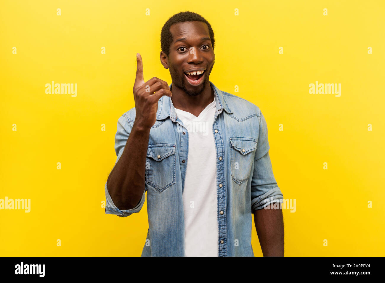 Portrait of creative inspired man in denim casual shirt pointing finger ...