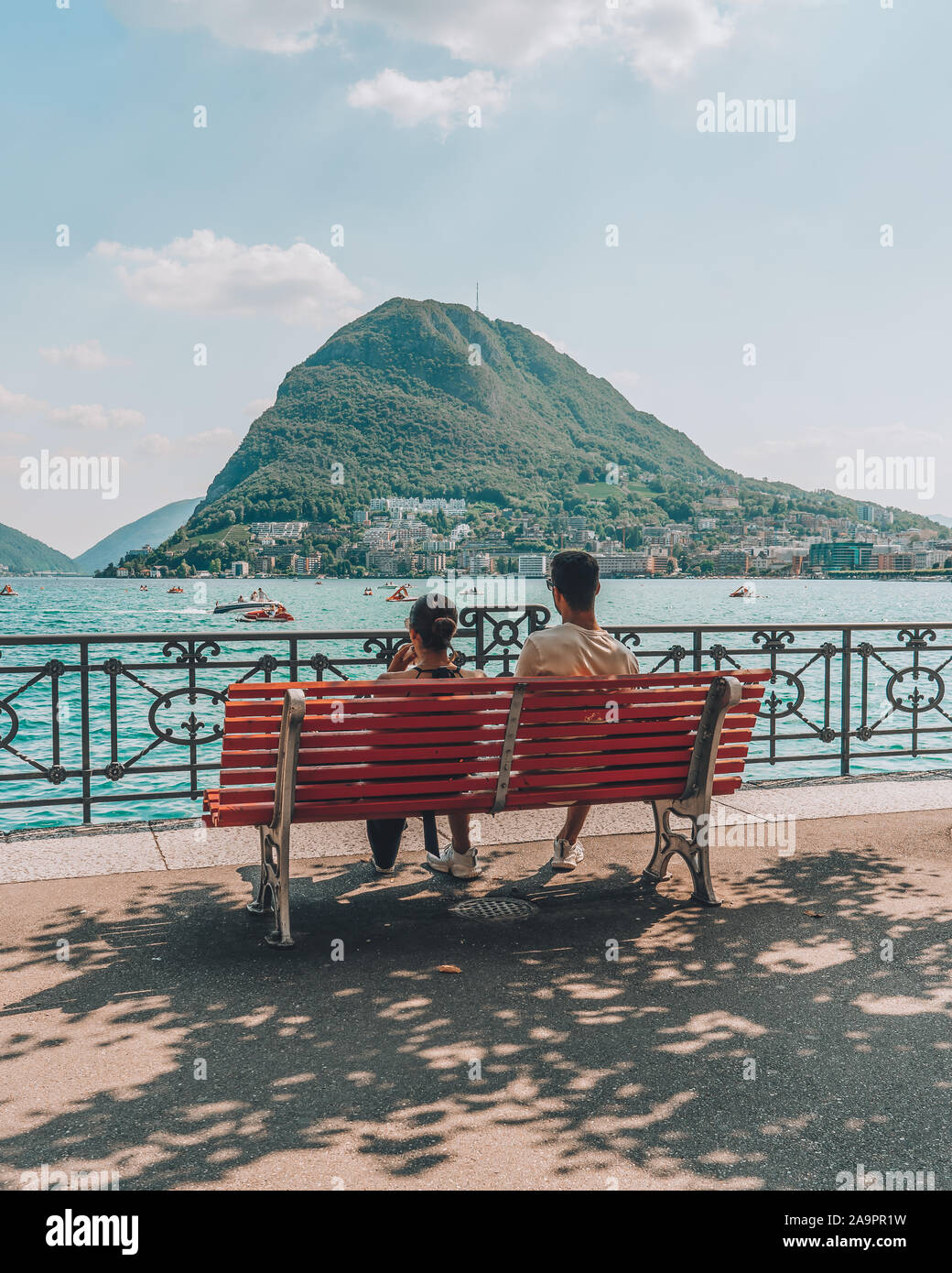 Lugano, Switzerland - August4, 2019: Lovers rest on red bench facing ...
