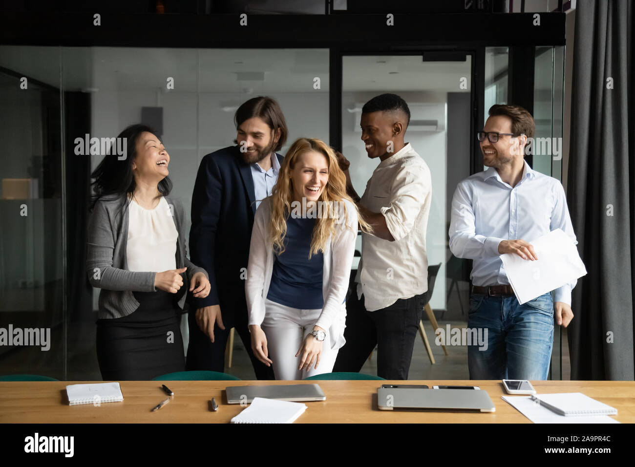 Overjoyed diverse colleagues having fun after workday at office Stock ...