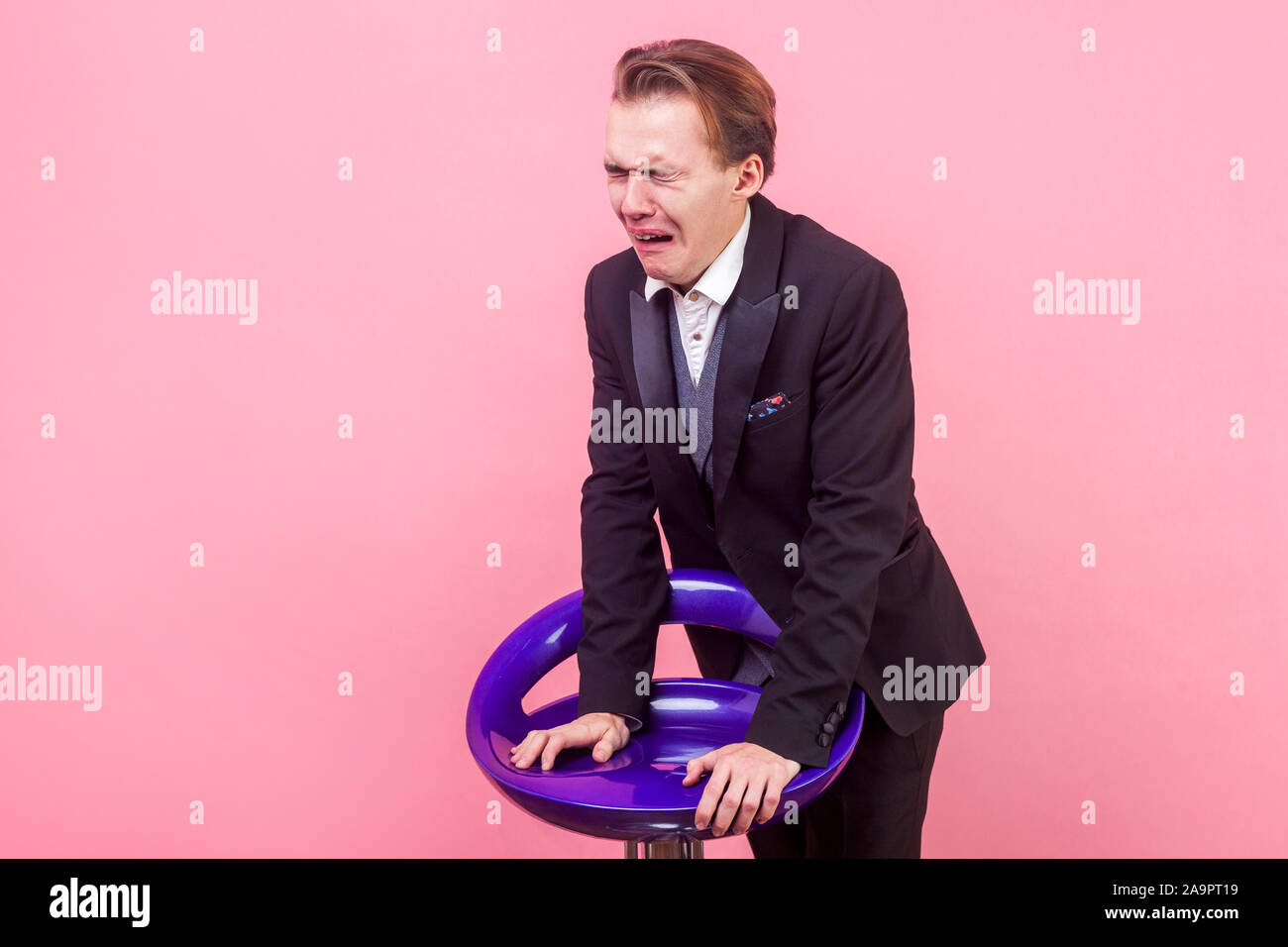 Portrait of dramatic desperate man in suit leaning on chair crying and ...