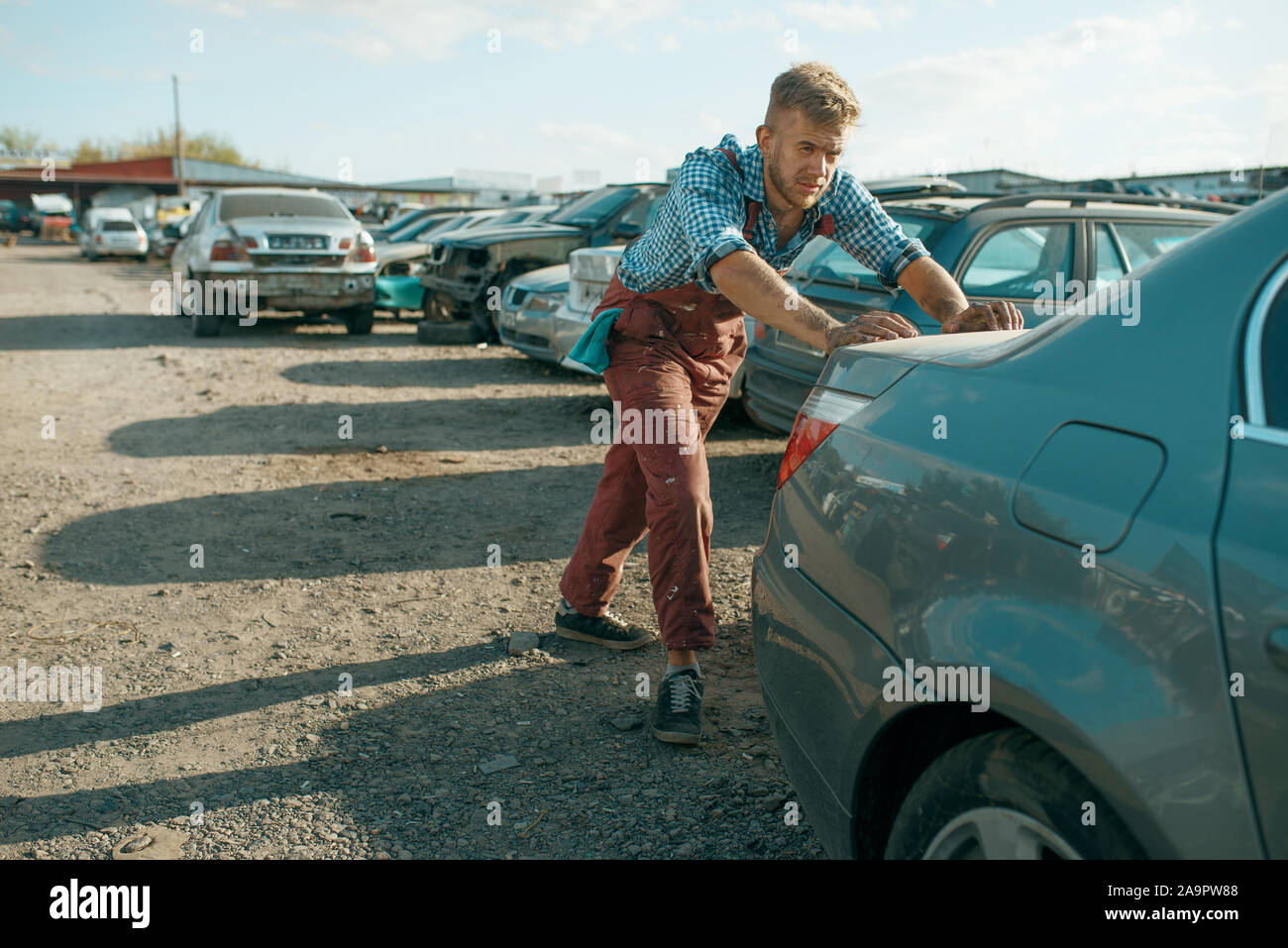 Male mechanic pushing the car on junkyard Stock Photo - Alamy