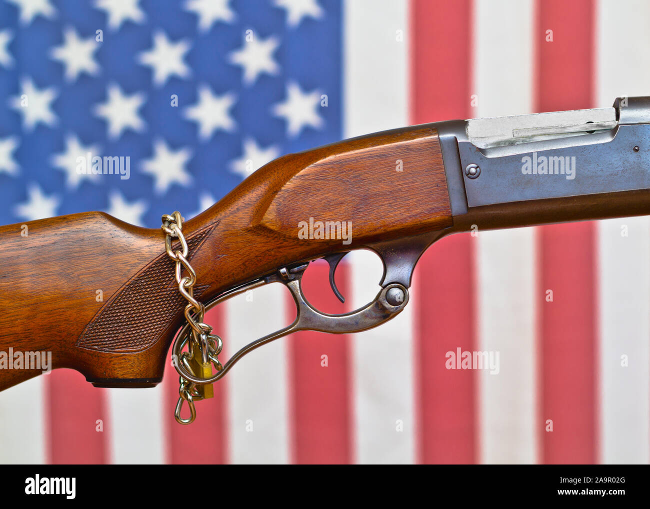 Lever action rifle with padlocked chain and American flag in background ...