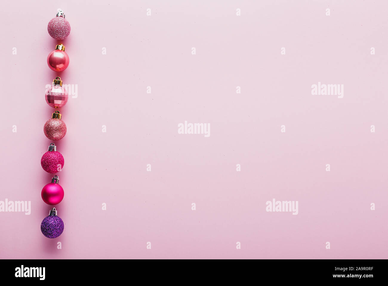 A border of pink and purple little Christmas balls on a pink background ...