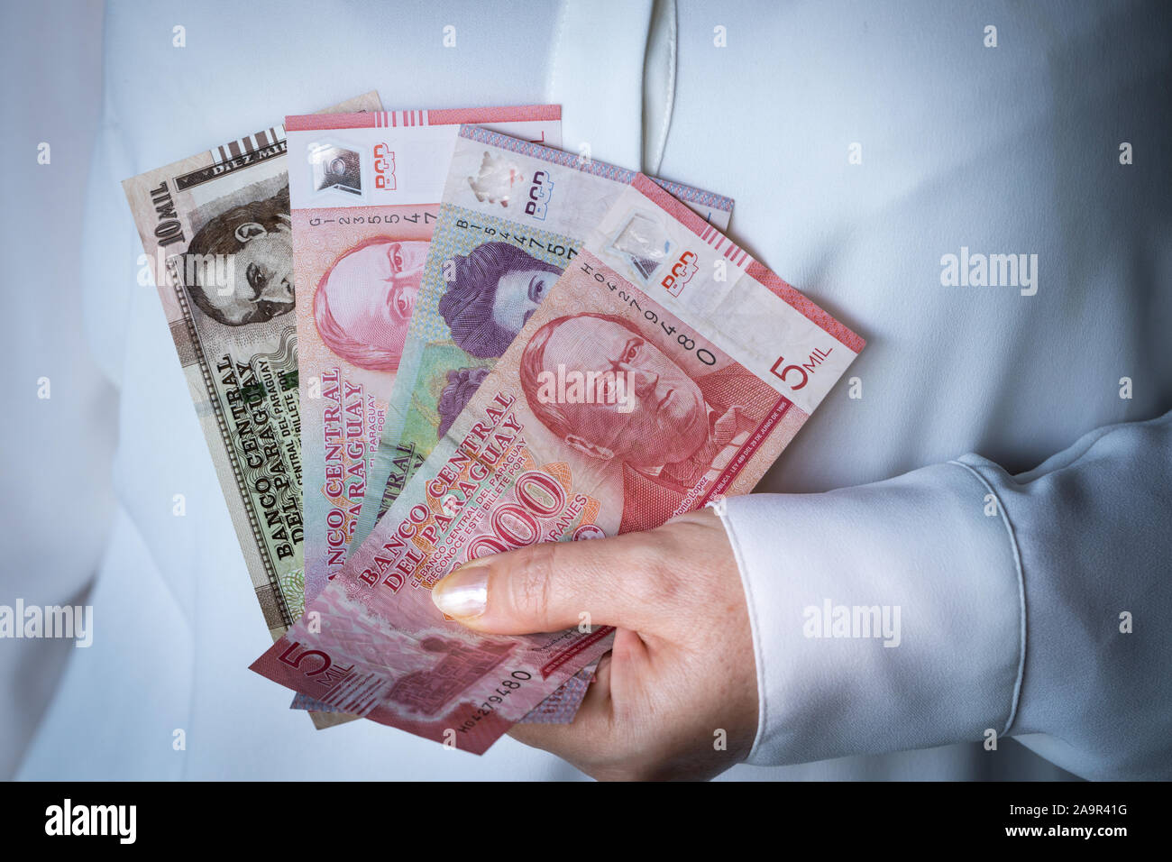the woman is holding Paraguayan money, Guaranies, various banknotes ...