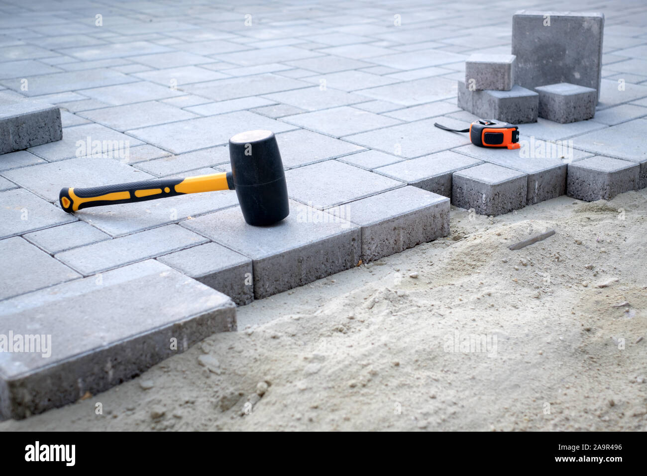 The master in yellow gloves lays paving stones in layers. Garden brick ...