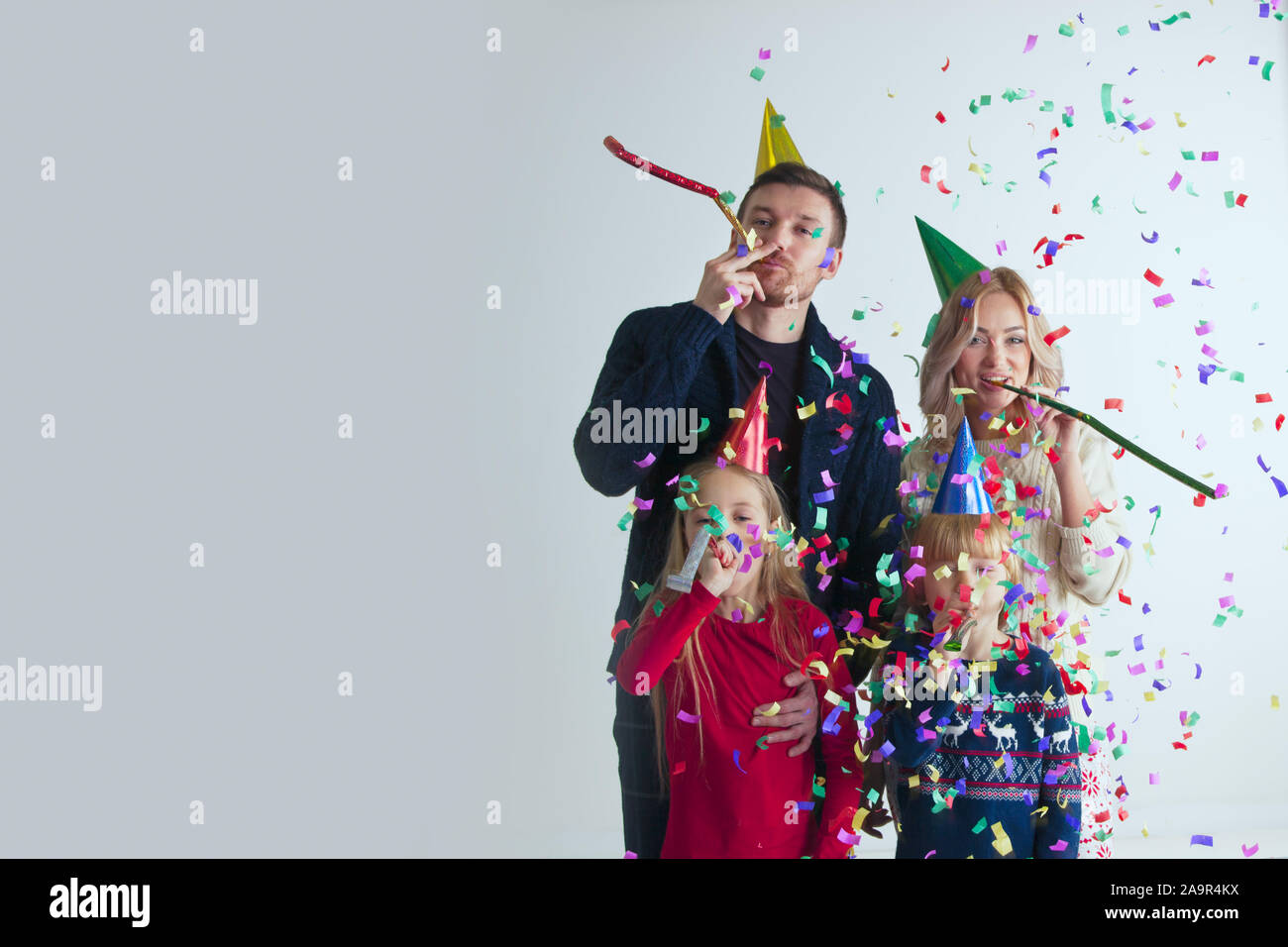 Family blowing party trumpets with confetti celebrating new year Stock ...