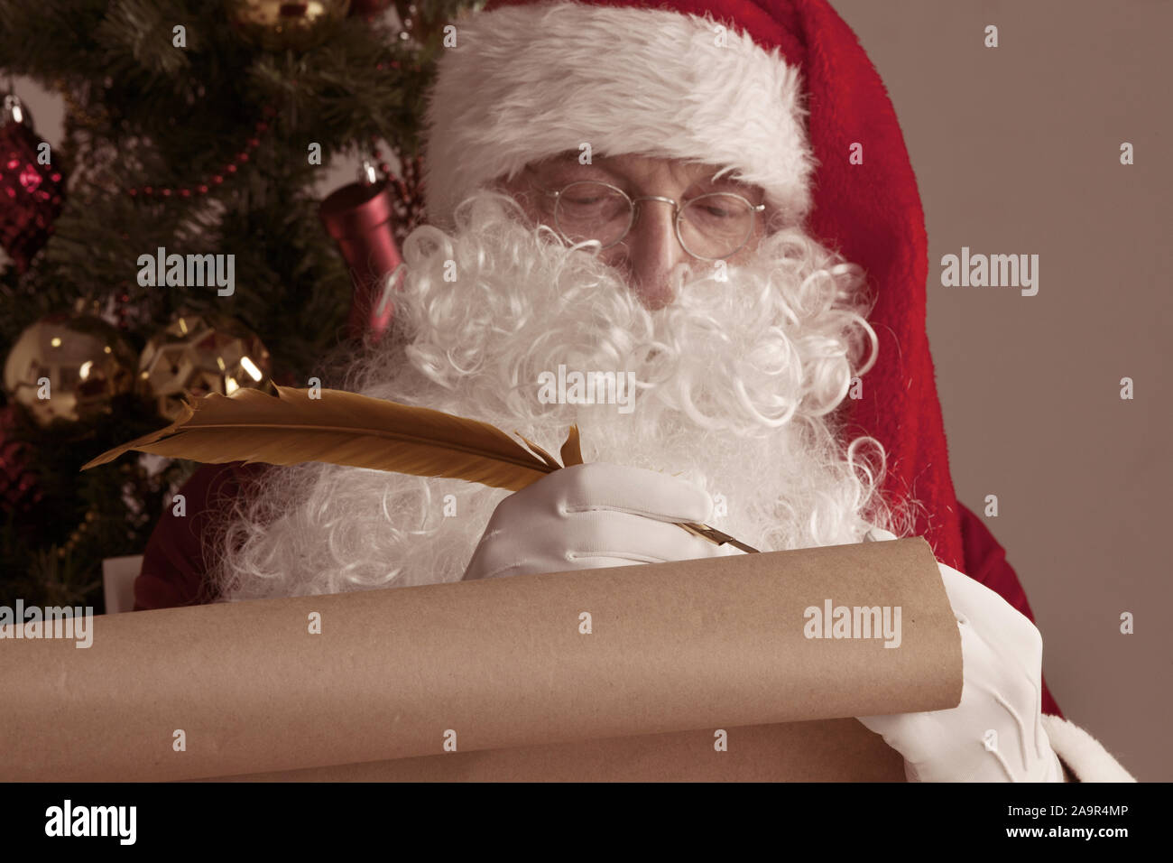 Santa Claus sitting at home and writing on old paper roll to do list ...