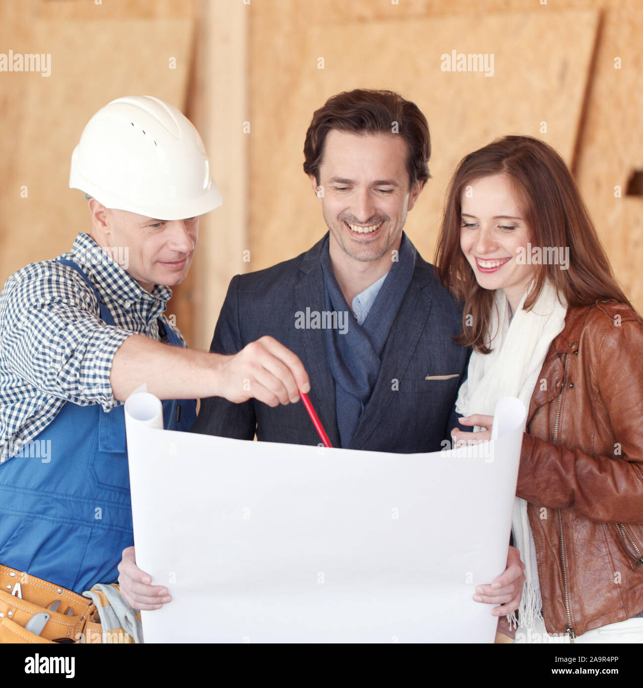 Foreman shows house design plans to smiling couple at construction site ...