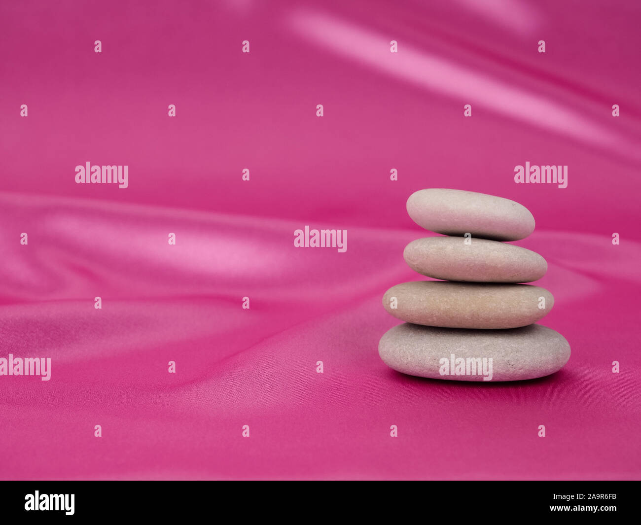 a pile of stones on a beautiful silk pink background. concept of calm ...