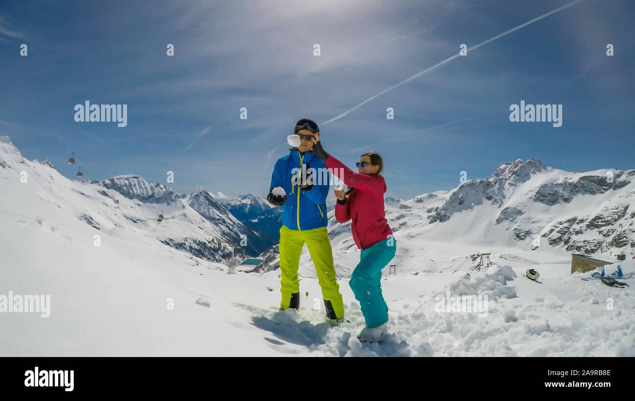 A couple in skiing outfits playing in the powder snow. They are ...