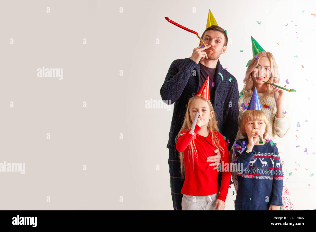 Family blowing party trumpets with confetti celebrating new year Stock ...